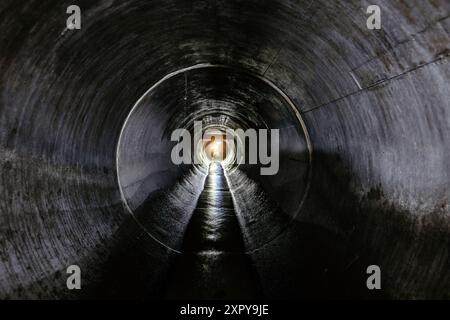 Inside underground urban sewer system. Sewage flowing in round sewer ...