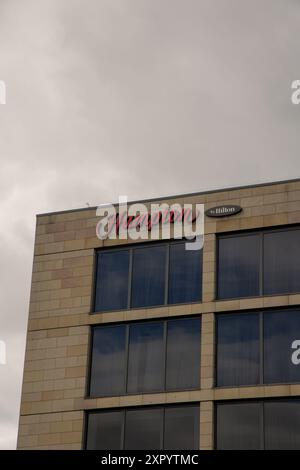 Sign with Hampton by Hilton logo at the top of the facade of the ...