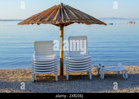 Mediterranean coast with sunbeds and straw sun umbrellas on the sandy ...