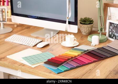 Workplace with modern computer and colorful fabric samples in fashion ...