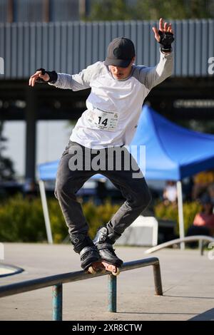 aggressive roller skater performing a trick on a railing in skatepark ...