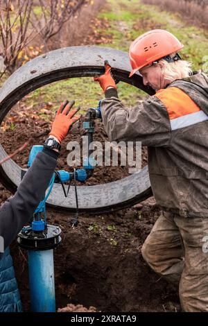 Workers install a water intake unit in a well. Installation of the ...