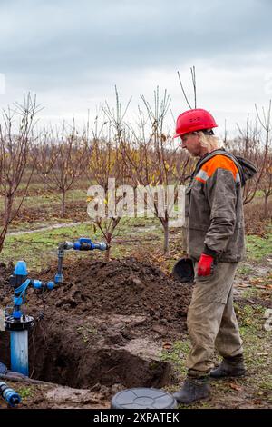 Workers install a water intake unit in a well. Installation of the ...