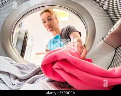Woman Doing Laundry Reaching Inside Washing Machine Stock Photo - Alamy