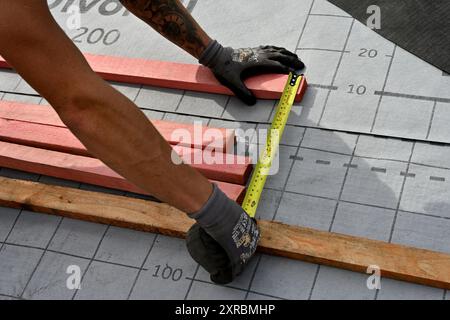 Roofing work, builder using tape measure to measure spacing between two ...