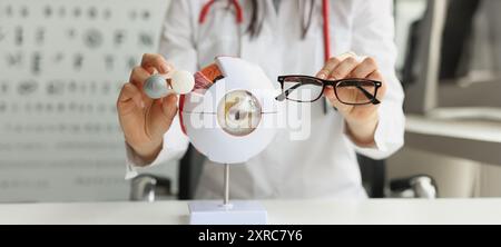 Optometrist woman holding glasses near anatomical model eye Stock Photo ...