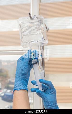Nurse connecting an IV drip. Nurse preparing and regulating infusion ...