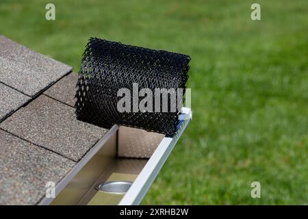 Installing gutter guard mesh screen on rain guttering. Home maintenance ...