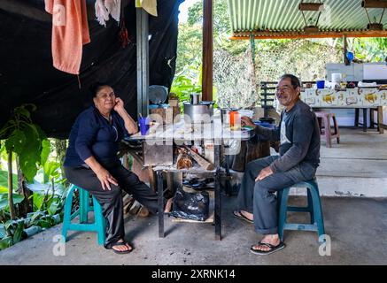 An old Guatemalan couple sitting and eating by their stove top at their ...