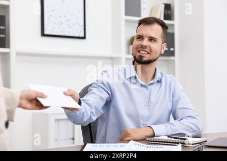 Smiling employee receiving envelope with salary from boss in office ...