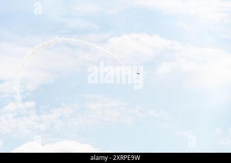 A single aircraft performing aerobatics leaving smoke trail behind ...