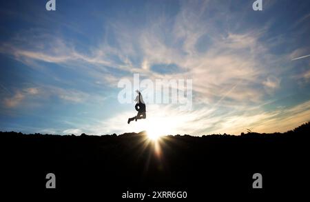 Young girl jumping against sunburst and blue sky Stock Photo - Alamy