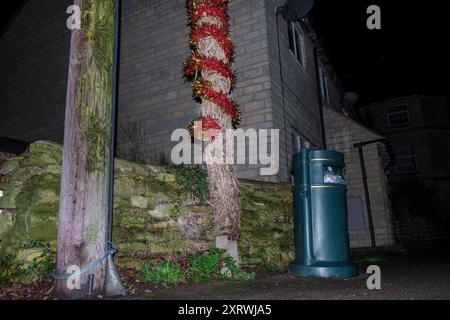 Christmas tinsel wrapped around an old ivy covered post on a street in ...
