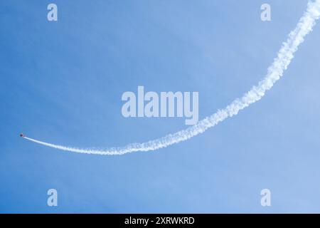 A small biplane permorms aerobatic loops trtailing vapor in a blue sky ...
