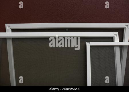 Set of window screens near brown wall Stock Photo - Alamy