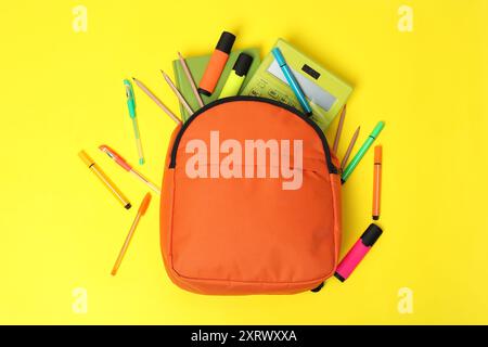 Orange backpack and different school supplies on light blue background ...