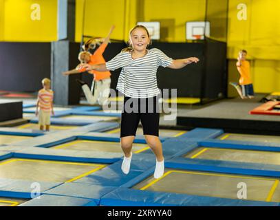 Tween girl bouncing on trampoline in indoor amusement park Stock Photo ...