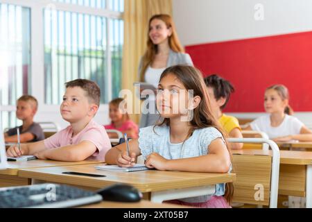 Smiling diligent tween schoolgirl studying with classmates Stock Photo ...