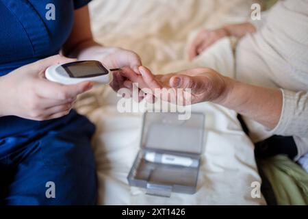 Nursing professional measuring the glucose of a patient with diabetes ...