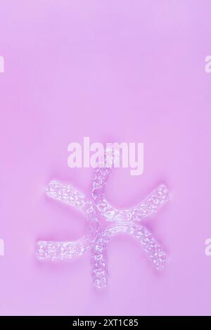 Invisible aligner teeth retainers on a pink background Stock Photo - Alamy