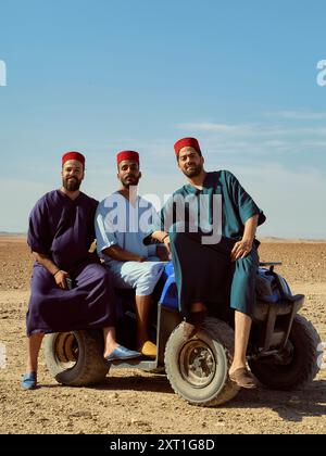 Three men wearing traditional fez hats pose confidently on a blue quad ...