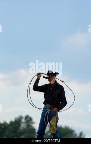 Cowboy in a hat and with a lasso standing in a field at sunset Stock ...