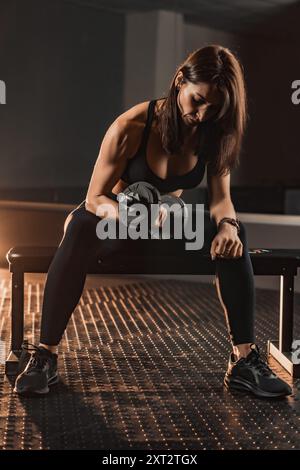 Young woman in sportswear and stylish sneakers tying shoe laces ...