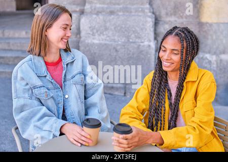 Two diverse women enjoying coffee in a cafe, looking at a digital ...