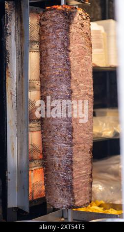 Chef skillfully cutting shawarma meat from a rotating skewer. Freshly ...