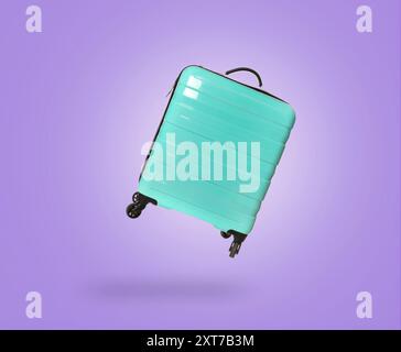Turquoise suitcase in air on light blue background Stock Photo - Alamy