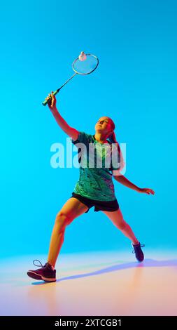 Young woman, badminton athlete leaping in motion to hit shuttlecock ...