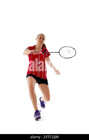 Young woman, badminton athlete leaping in motion to hit shuttlecock ...