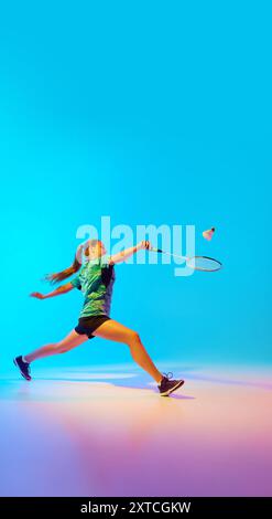 Young woman, badminton athlete leaping in motion to hit shuttlecock ...