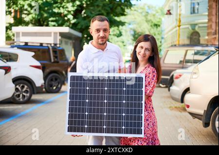 Cute couple holding portable solar panel. Young man and his wife ...