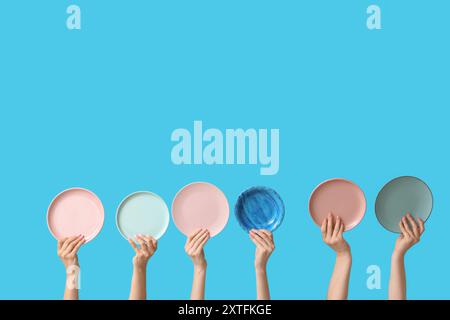 Hands holding empty plates on blue background Stock Photo - Alamy