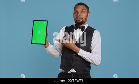 Bellman hotelier showing a tablet with green screen display in studio ...