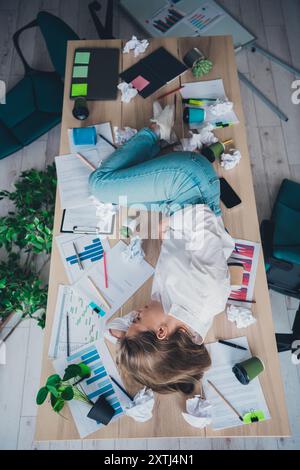 Vertical full size photo of upside down young woman lying messy desktop ...