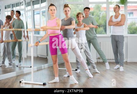 Group of teenagers practice ballet moves in classical dance studio ...