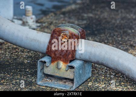 Rusty metal clamp holding electrical conduit on rooftop Stock Photo - Alamy