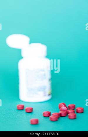 jar of pills and a handful of red round pills on a dark green ...
