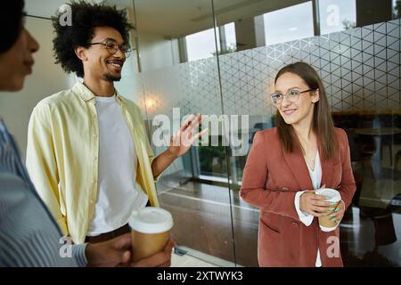 Three colleagues chat and enjoy coffee in a modern office setting Stock ...