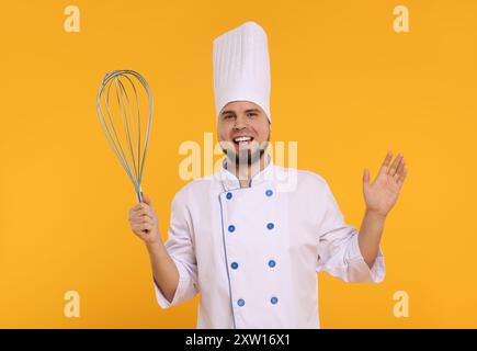 Happy pastry chef with big whisk on red background Stock Photo - Alamy
