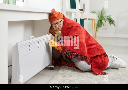 Man warms up by electric heater as he gets cold inside his house or apartment in winter Stock Photo Alamy
