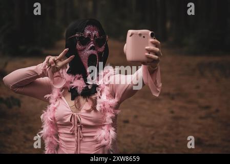 woman posing in pink scream halloween costume with dork forest in ...