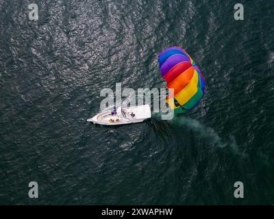 Drone video of a colorful parasail soaring over the open ocean, towed ...