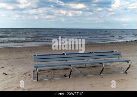 A bench faces the ocean, surrounded by soft sand and gentle waves Stock ...