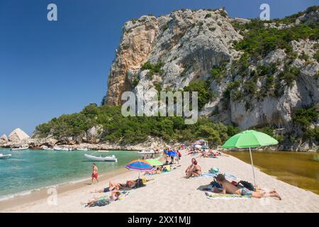 Tourists relaxing on the beach with views towards the sea and cliffs ...