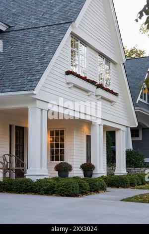 White clapboard house with large front dormer and pillars in front ...