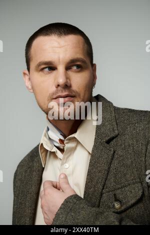 A man poses in a studio, adjusting his jacket with a confident air ...