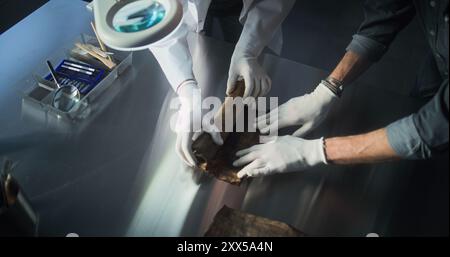 Two archaeologists in gloves carefully roll out ancient Egyptian ...